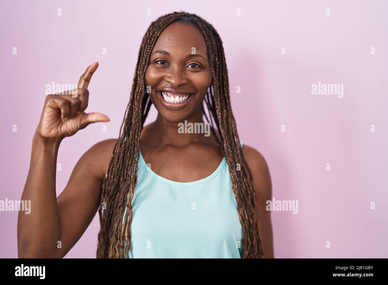 African american woman standing over pink background smiling and ...