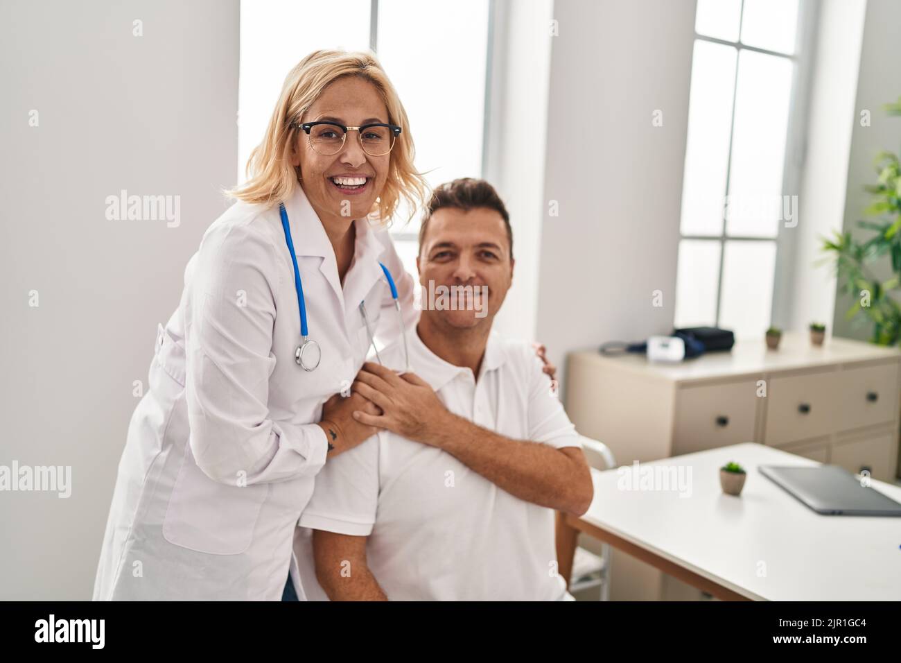 Middle age man and woman doctor and patient hugging each other having ...