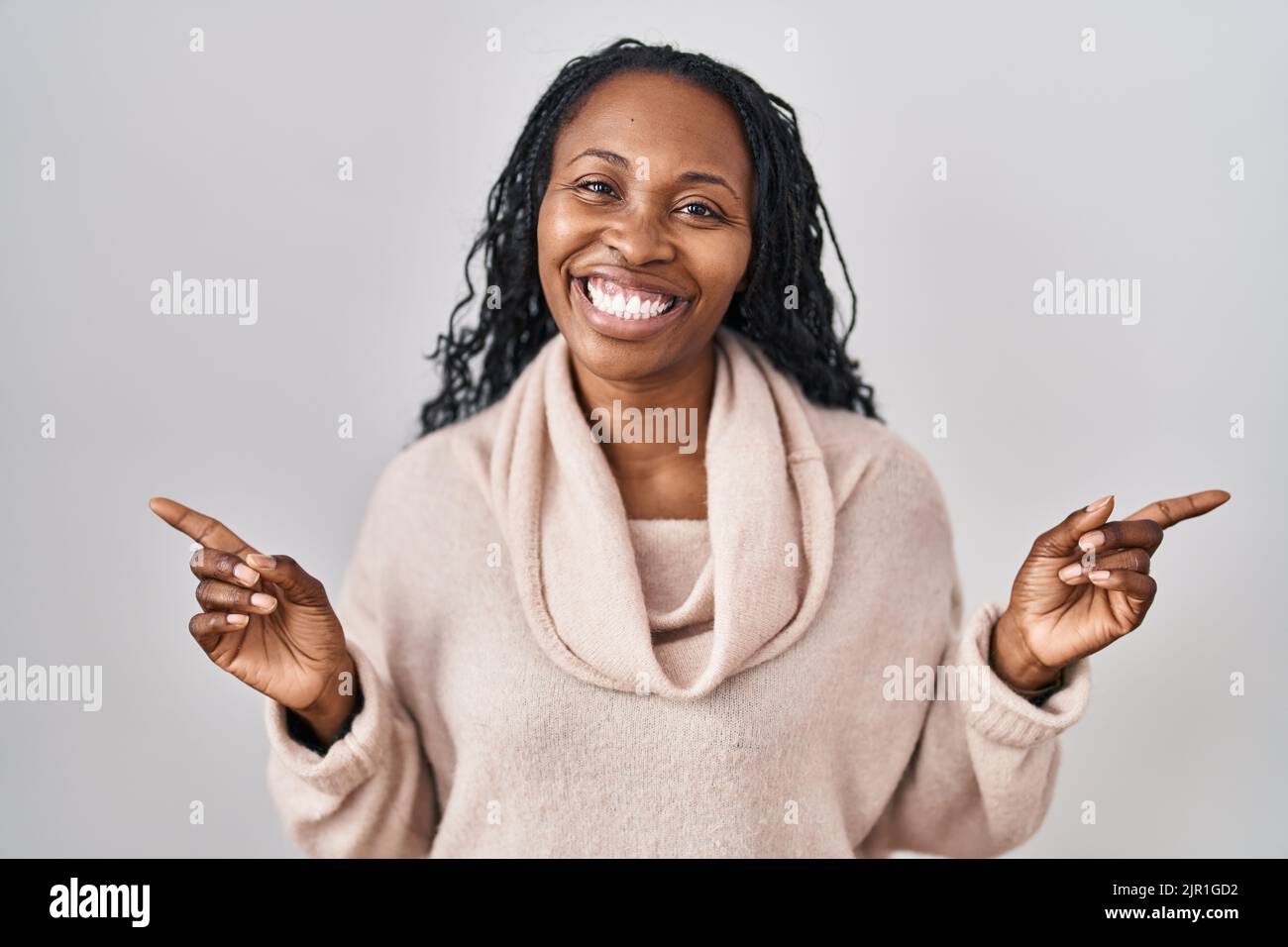 African woman standing over white background smiling confident pointing ...