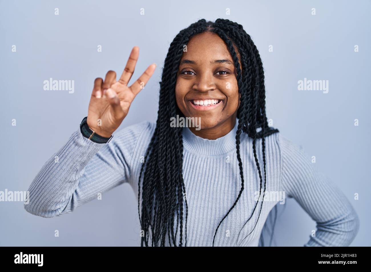 African american woman standing over blue background smiling looking to ...