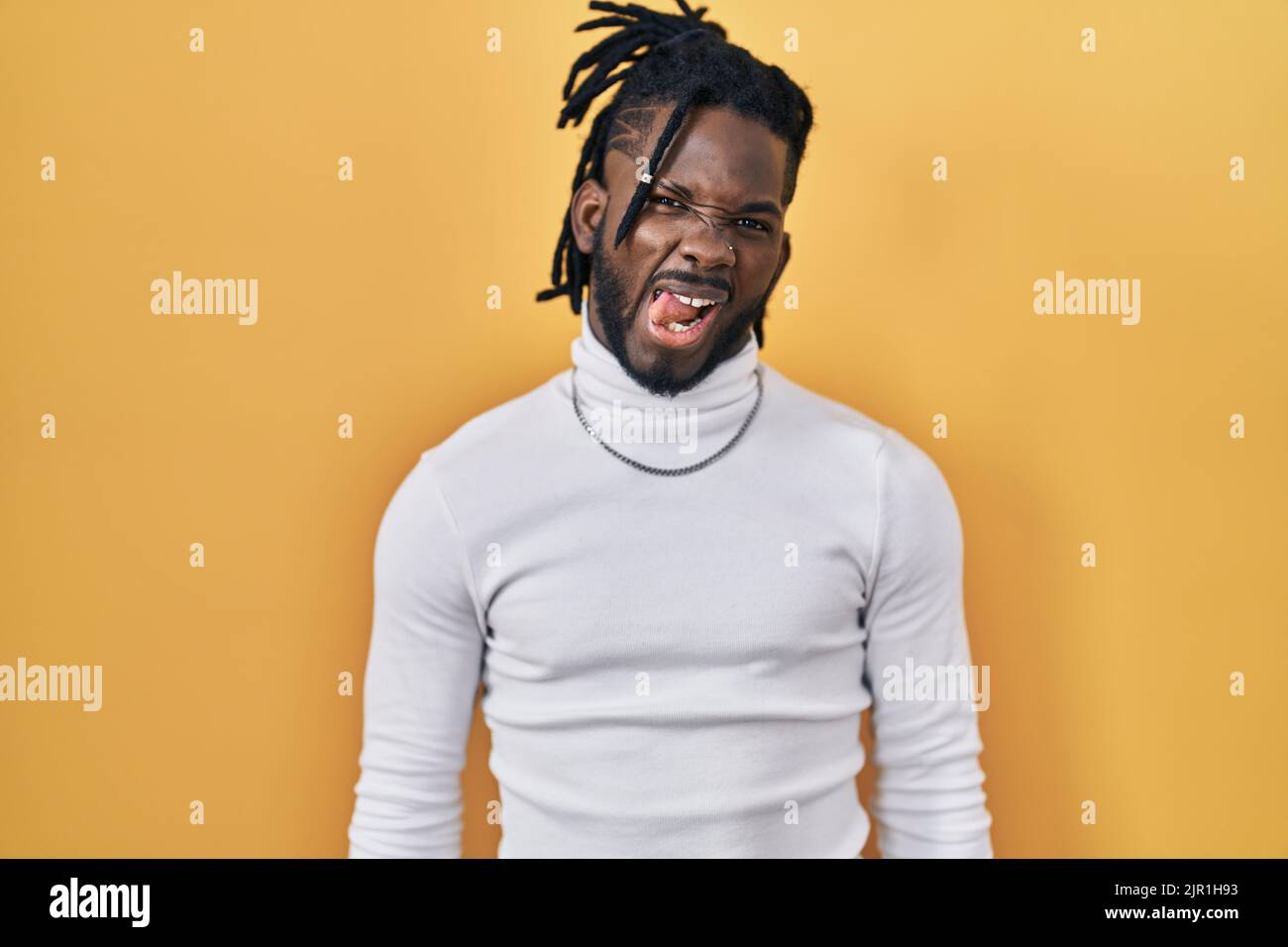 African man with dreadlocks wearing turtleneck sweater over yellow ...