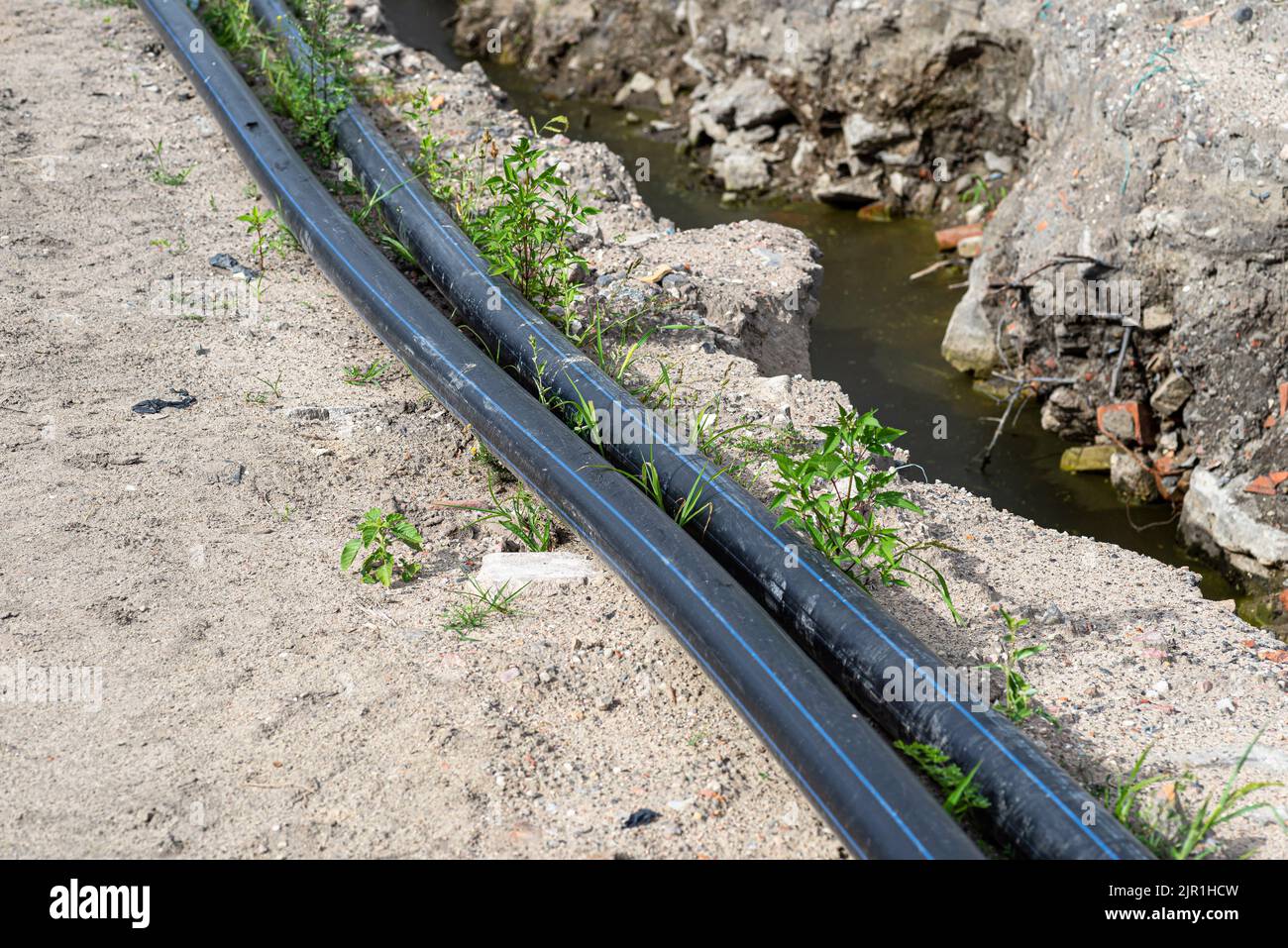 Plastic water pipe lying along the ditch with high groundwater, water ...