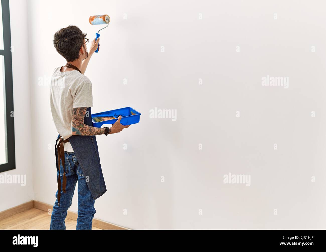 Painter painting wall using roller at home Stock Photo - Alamy