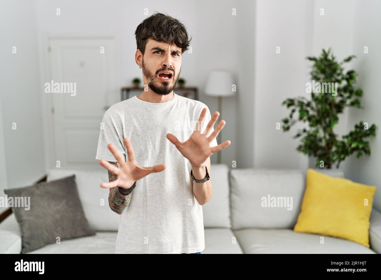 Hispanic man with beard at the living room at home afraid and terrified ...