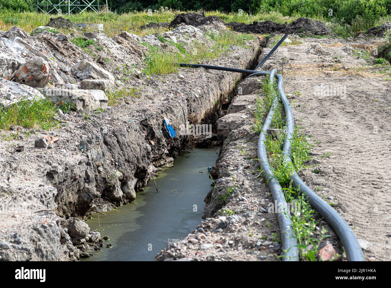 Plastic water pipe lying along the ditch with high groundwater, water ...