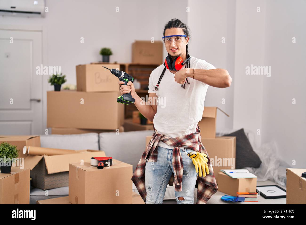 Hispanic man with long hair holding screwdriver at new home pointing ...