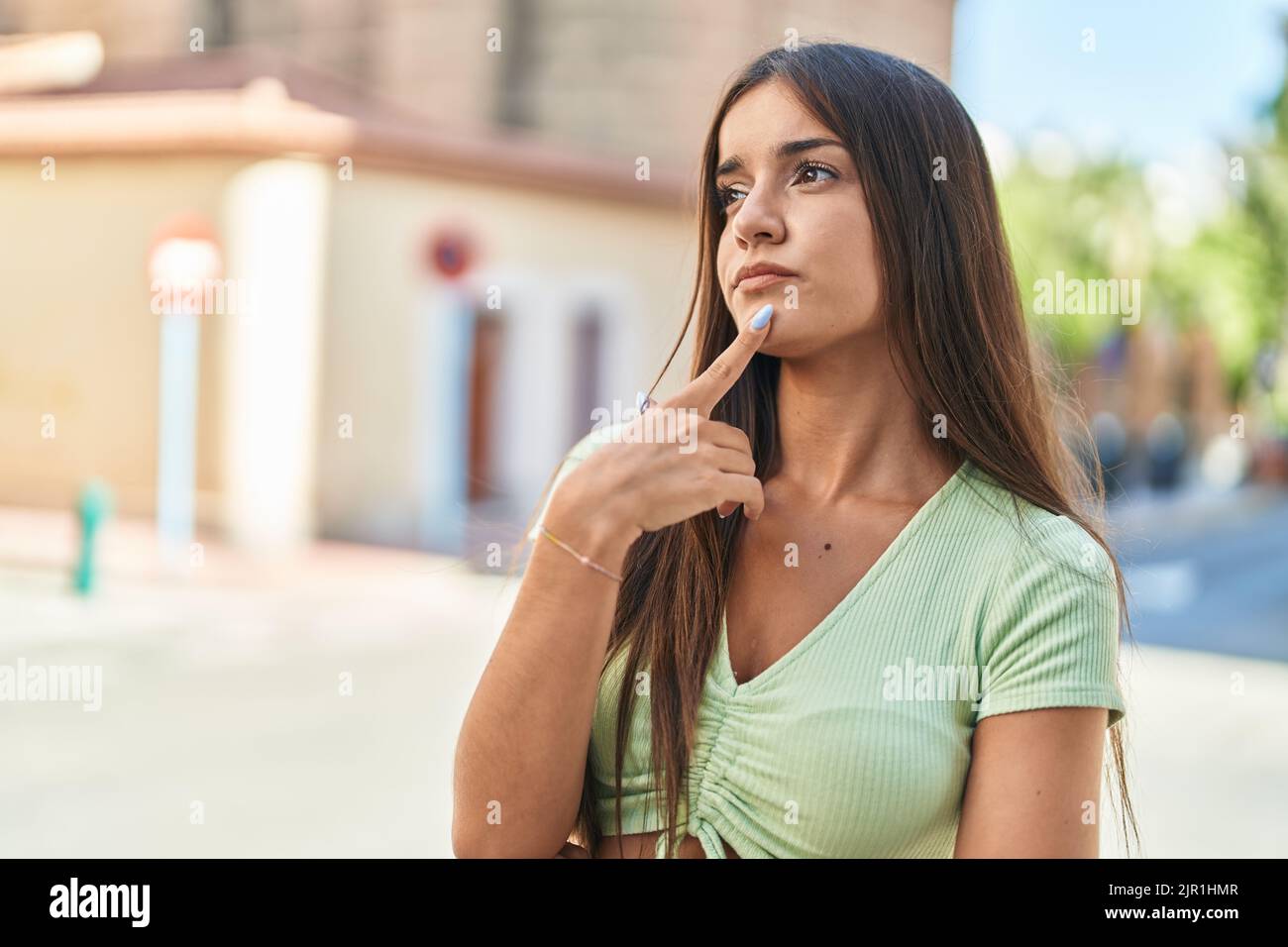 Young beautiful hispanic woman standing with doubt expression at street ...
