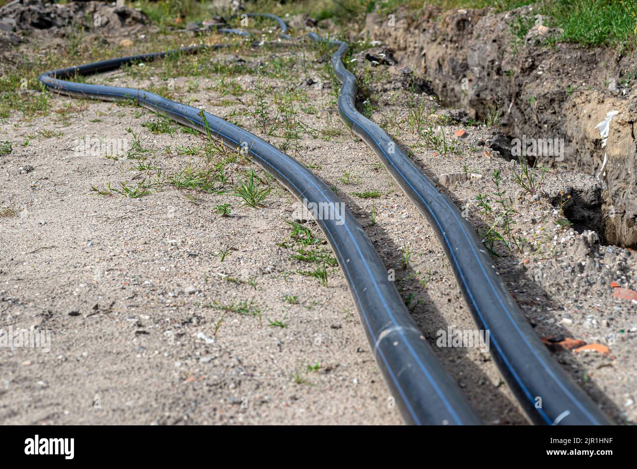 Plastic water pipe lying along the ditch with high groundwater, water ...