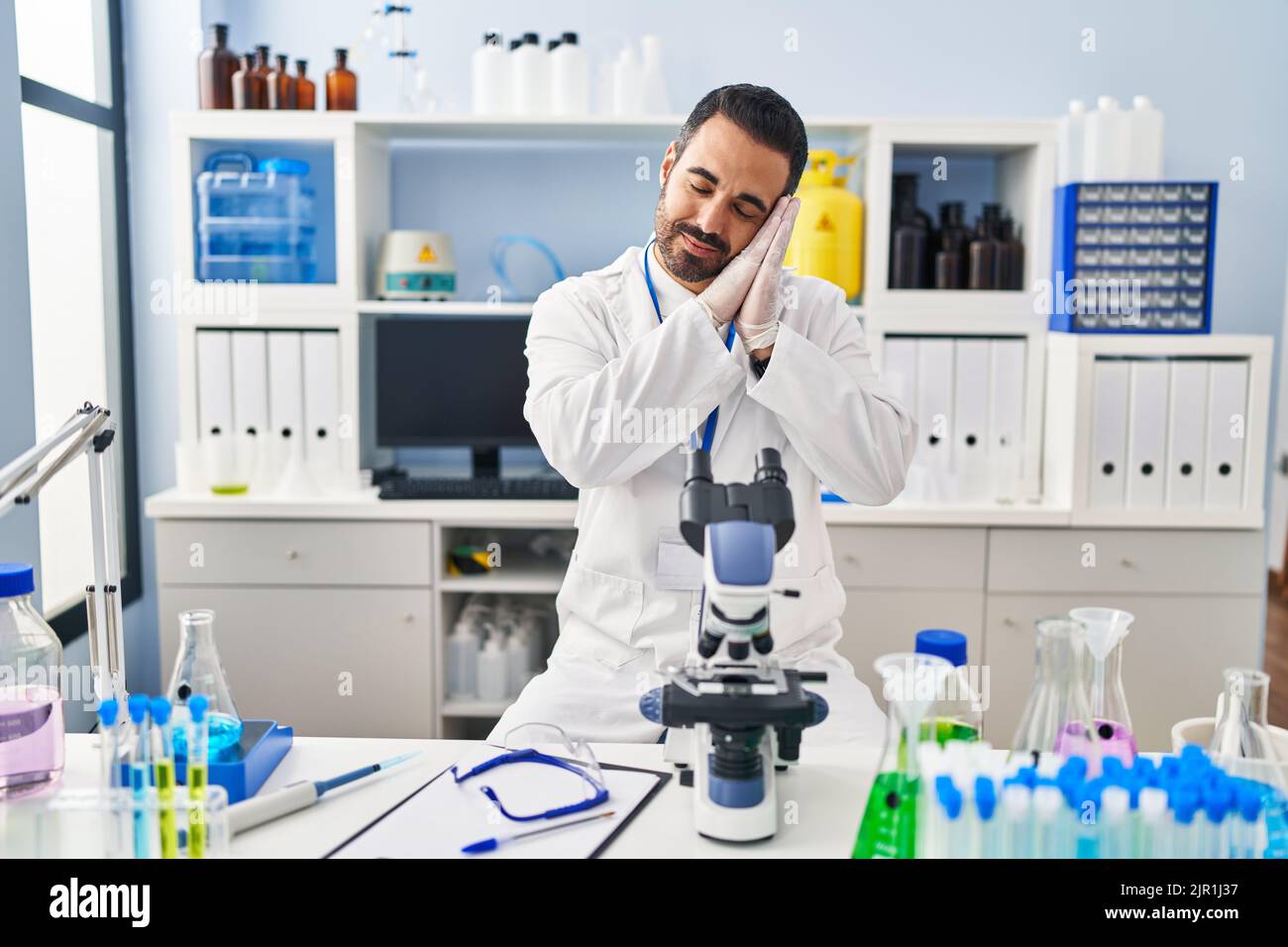 Young hispanic man with beard working at scientist laboratory sleeping ...