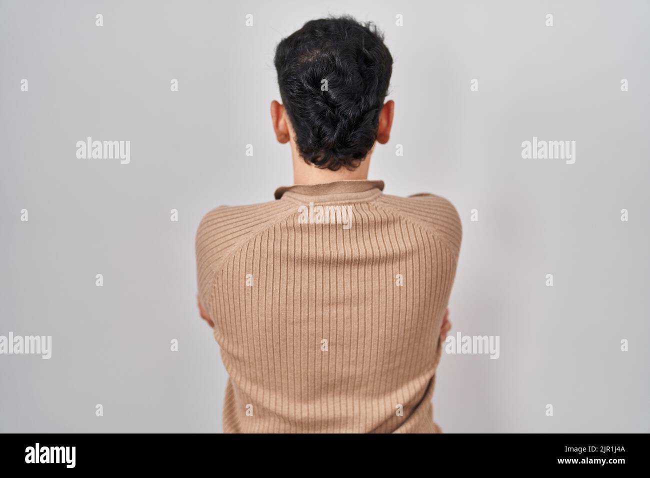 Non binary person standing over isolated background standing backwards ...