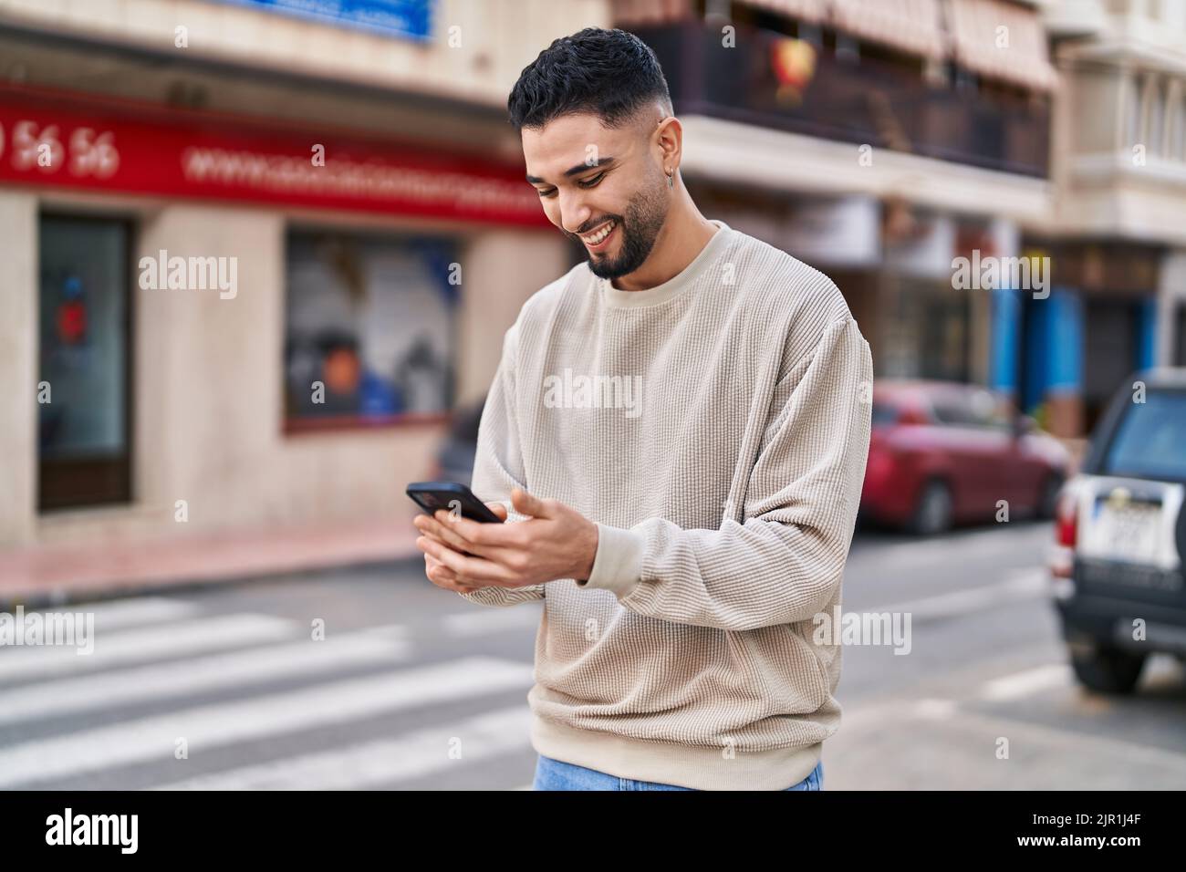 Young arab man smiling confident using smartphone at street Stock Photo ...