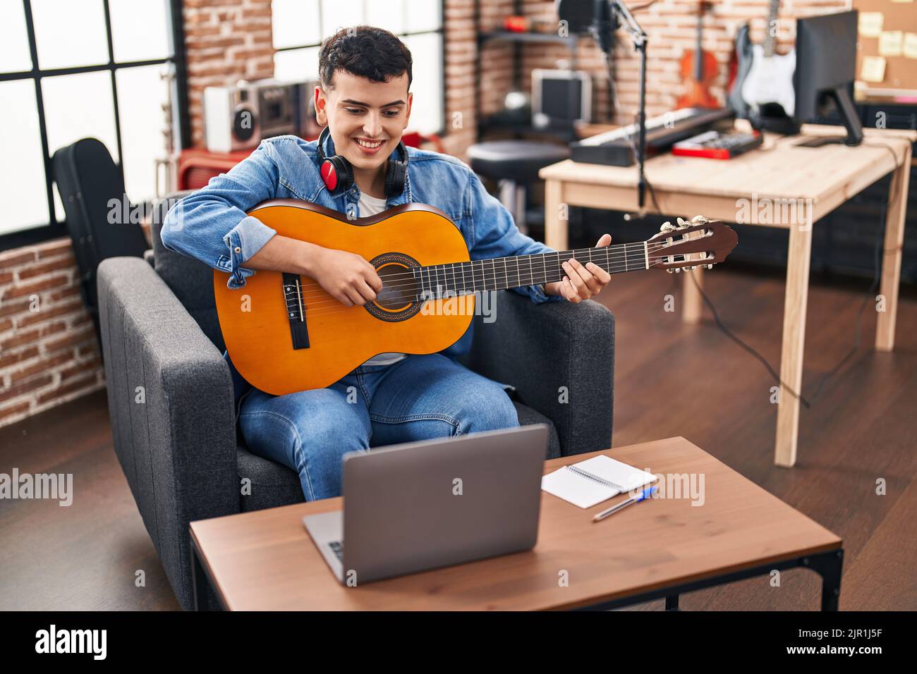 Young non binary man musician having online classical guitar lesson at ...