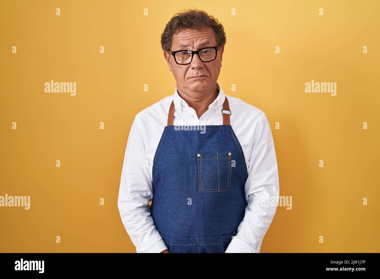 Middle age hispanic man wearing professional cook apron depressed and ...