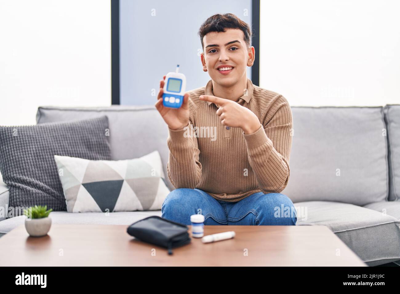 Non binary person using blood pressure monitor smiling happy pointing with hand and finger Stock ...