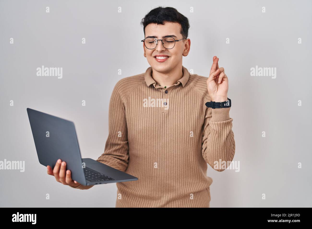 Non binary person using computer laptop gesturing finger crossed ...