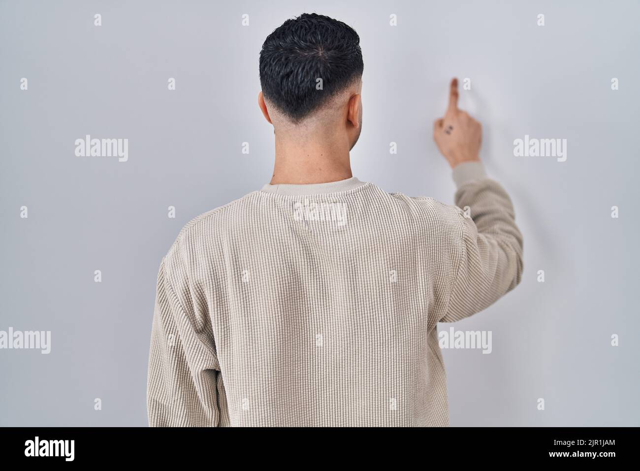 Young handsome man standing over isolated background posing backwards ...