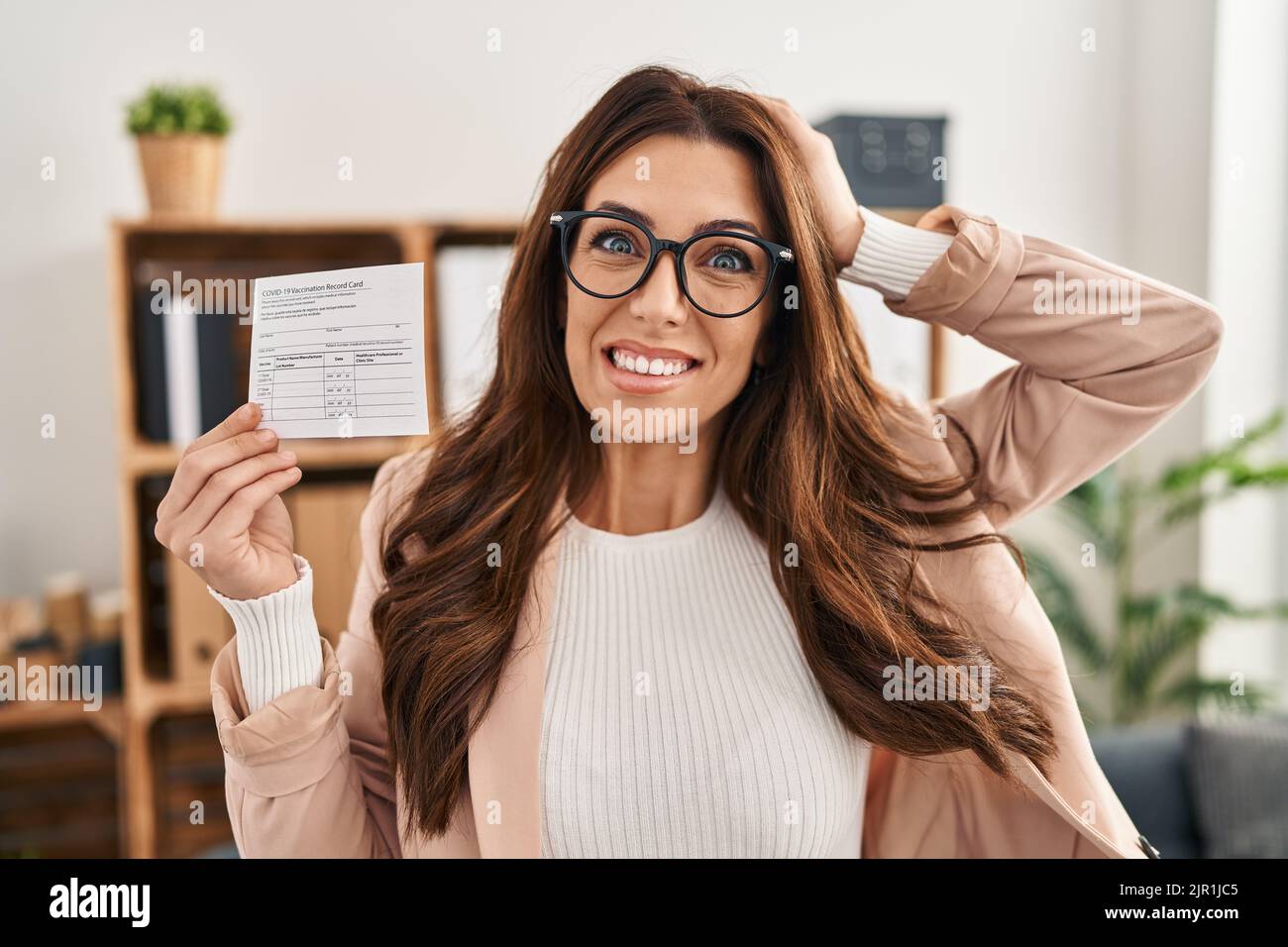 Young brunette woman holding covid record card stressed and frustrated ...