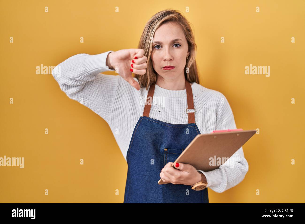 Young blonde woman wearing professional waitress apron holding ...