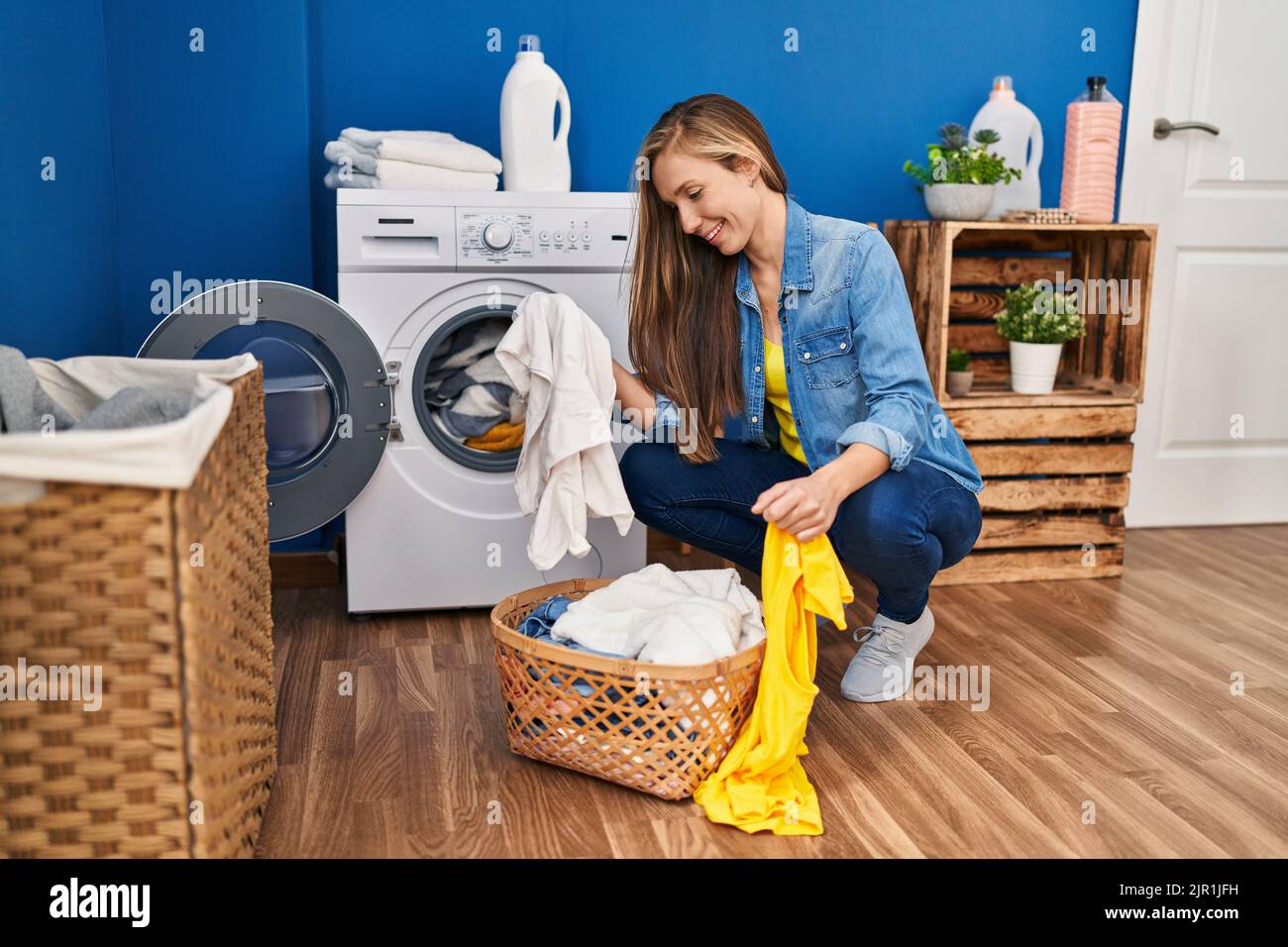 Young blonde woman smiling confident washing clothes at laundry room ...