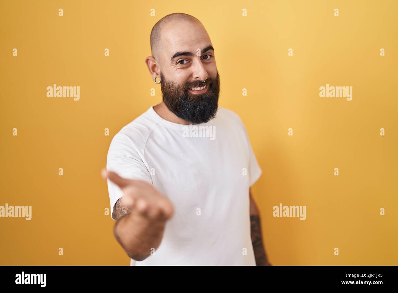Young hispanic man with beard and tattoos standing over yellow ...