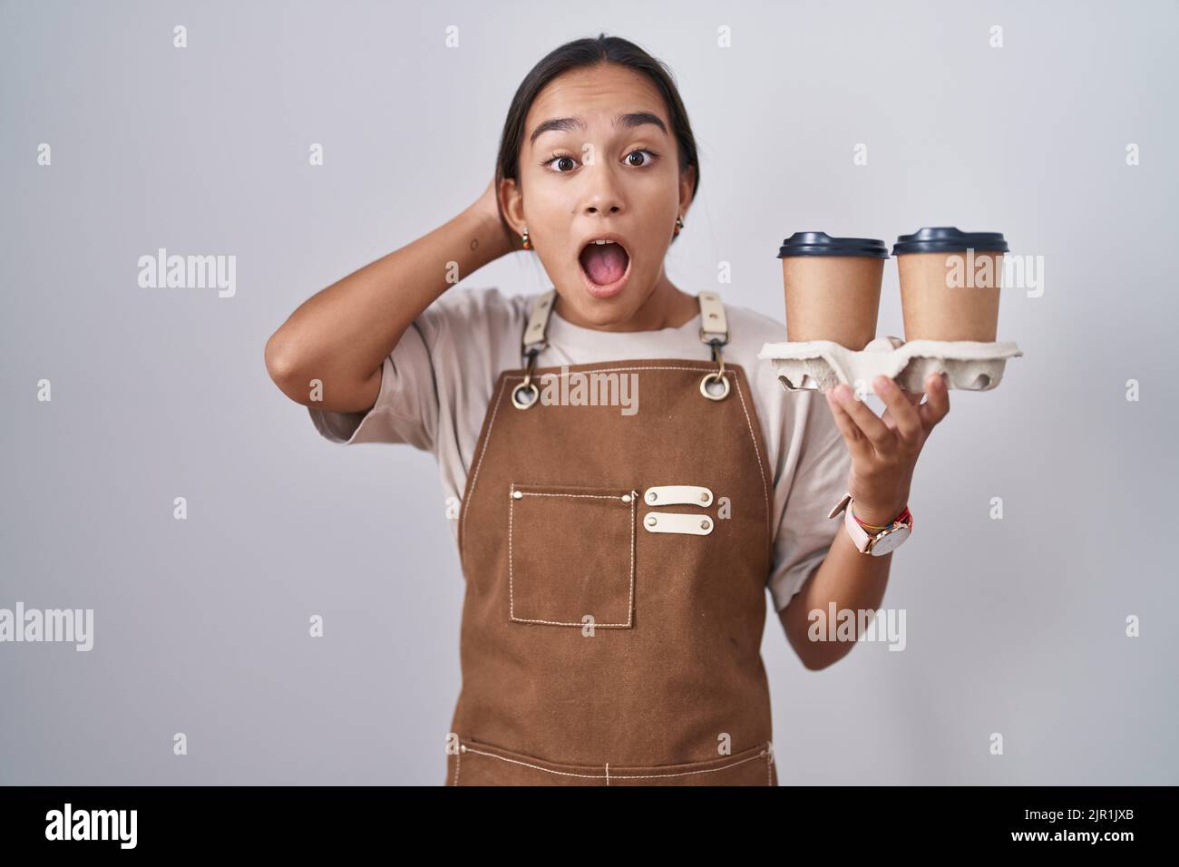 Young hispanic woman wearing professional waitress apron holding coffee ...