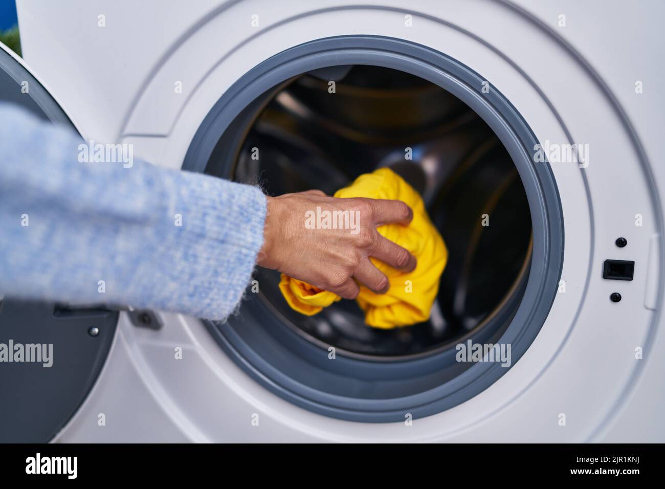 Young woman putting clothes in washing machine at laundry room Stock ...