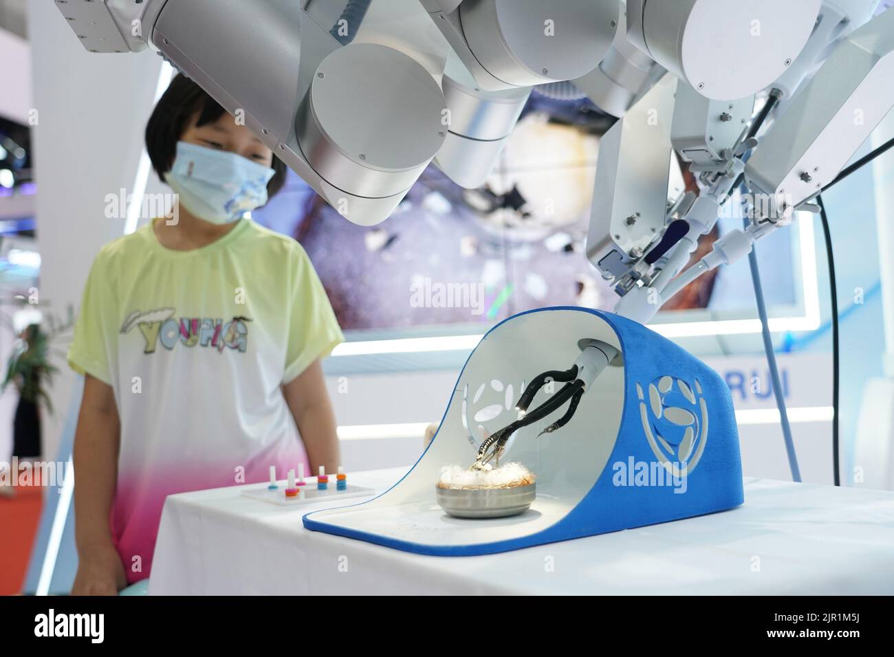 Beijing, China. 18th Aug, 2022. A girl looks at a surgery robot during ...