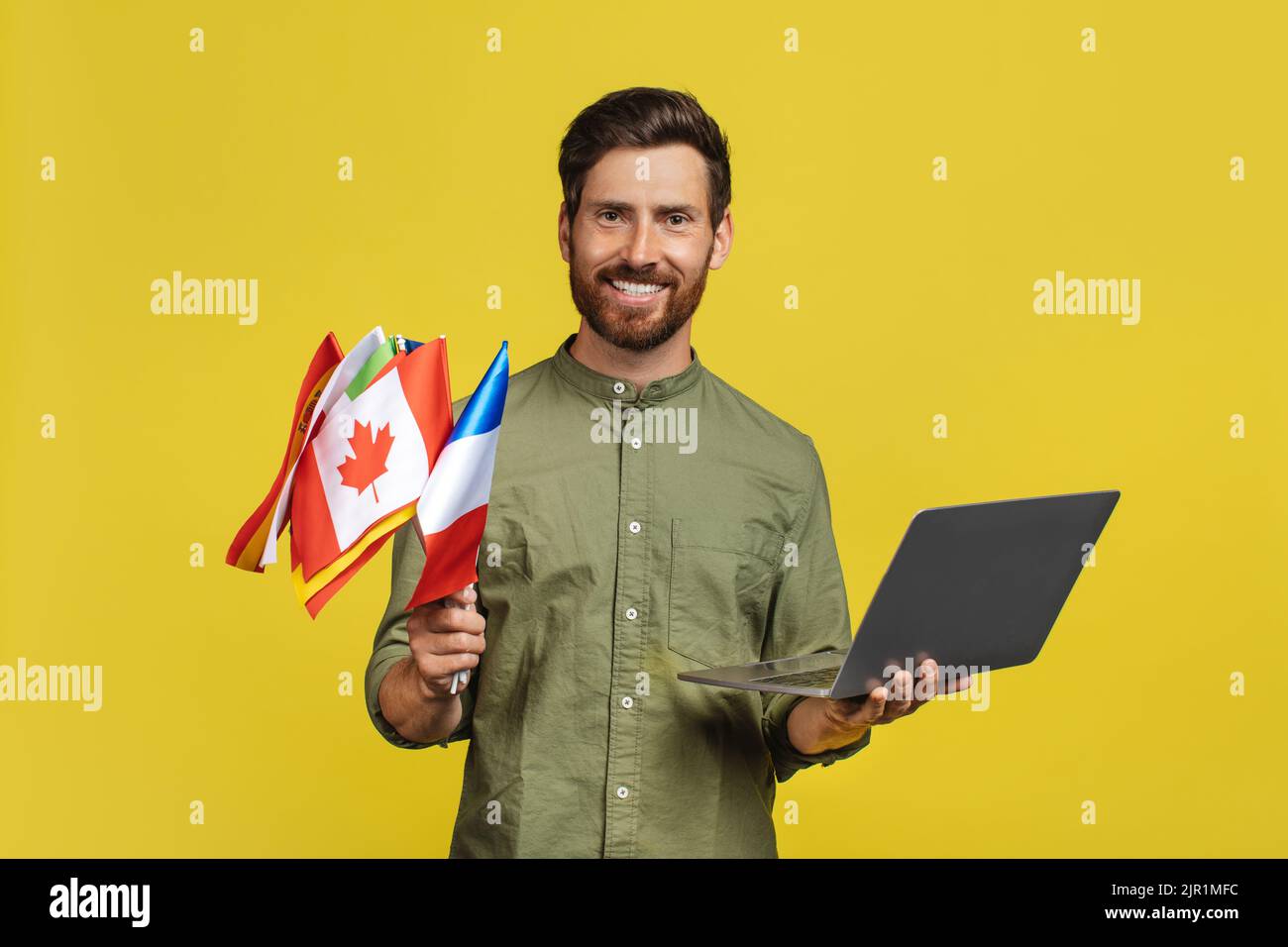 Learn foreign languages. Happy man holding laptop and international ...