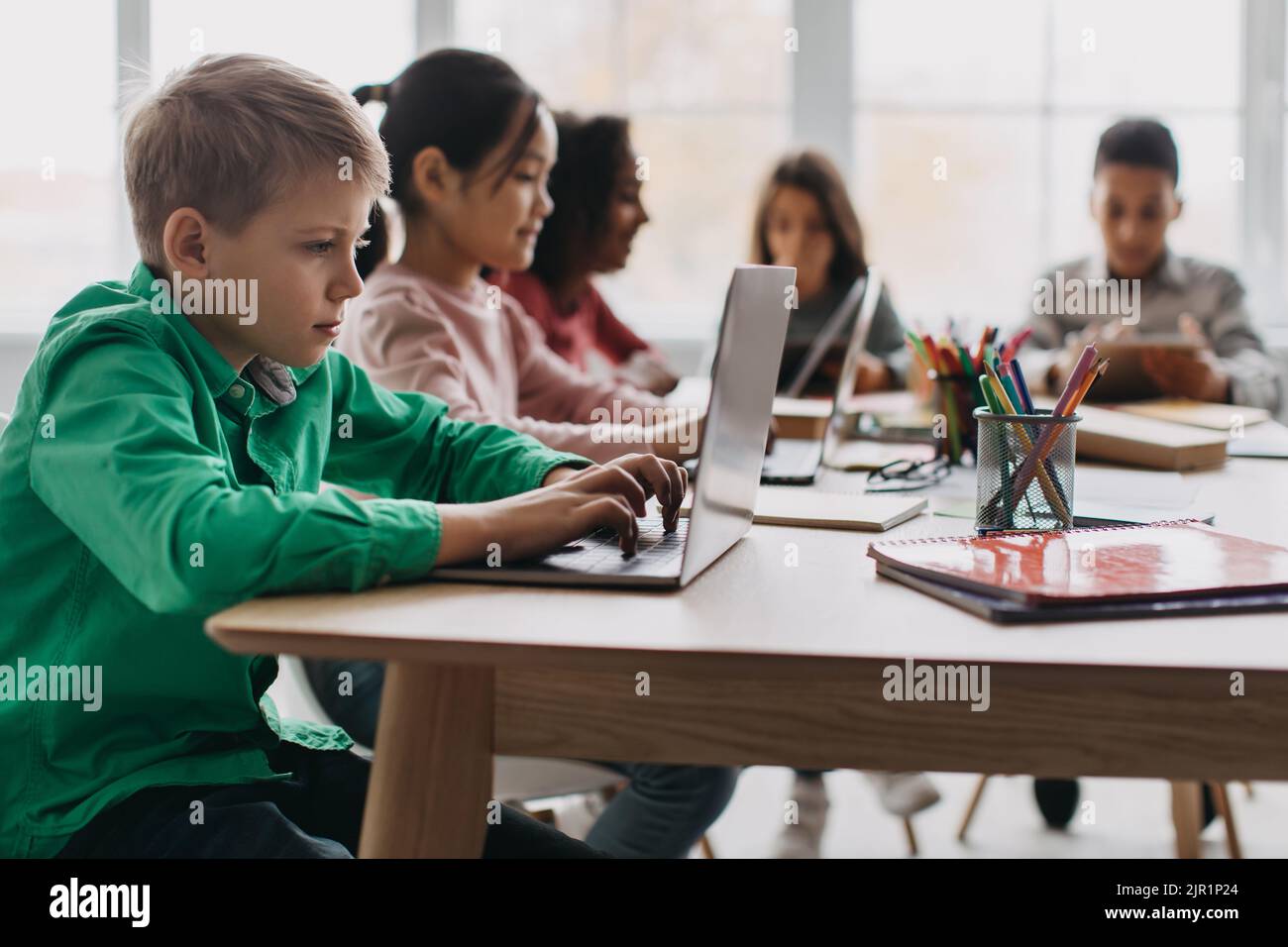Boy Using Laptop Sitting With Multiethnic Classmates In Modern ...