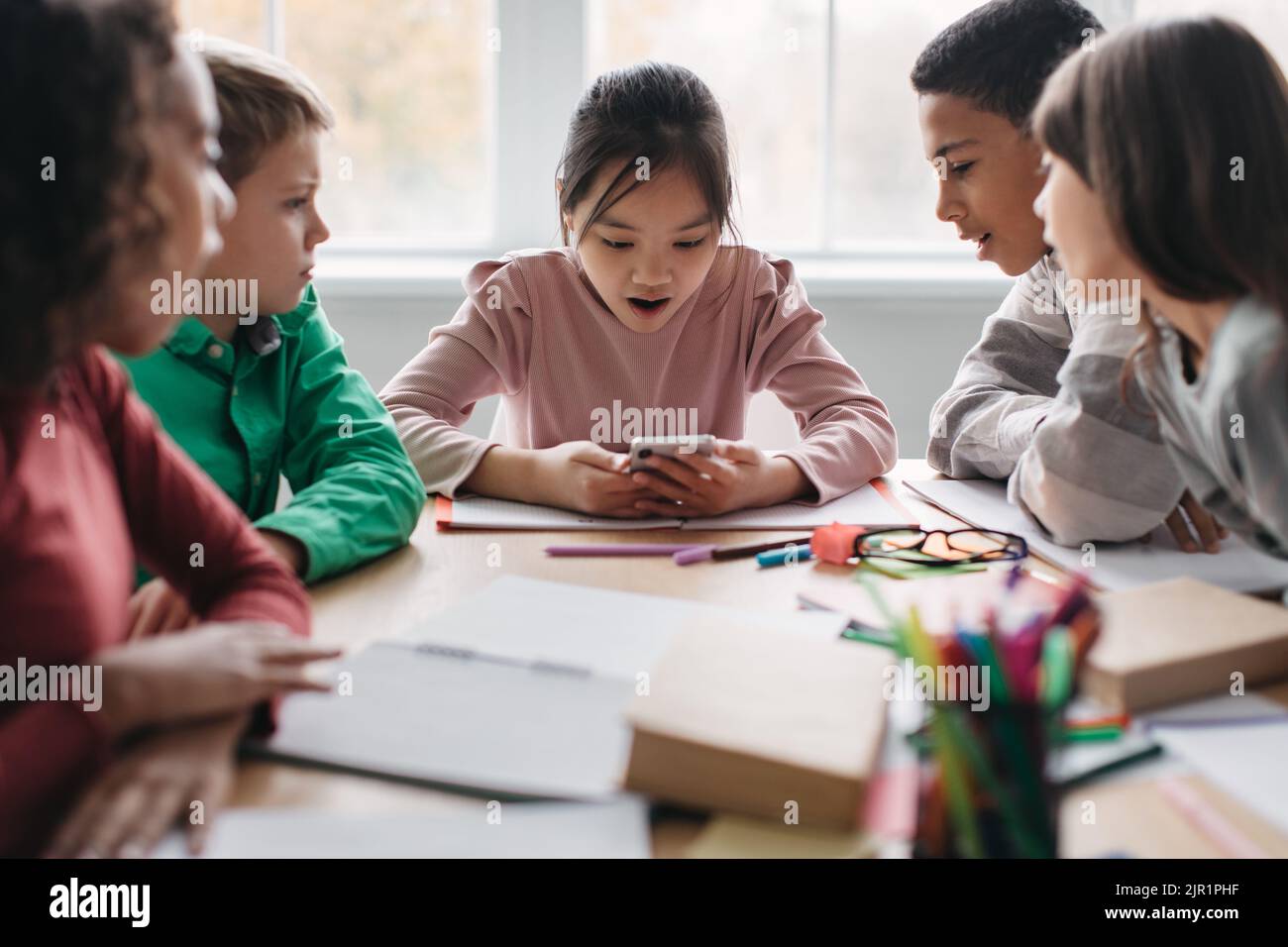 Classmates Using Smartphone Sitting At Desk During Break In Classroom ...