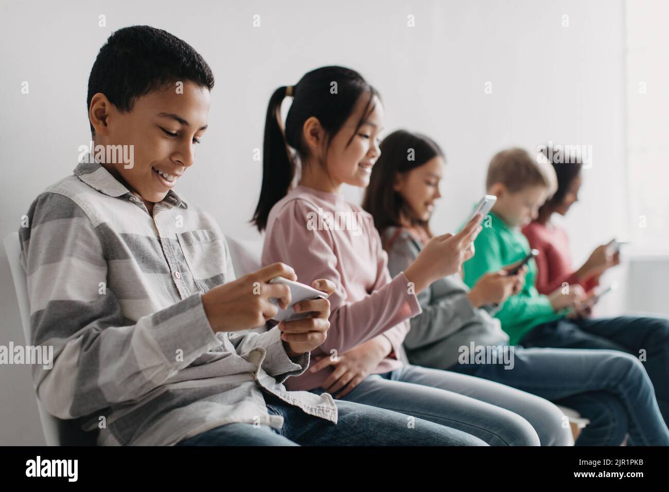 Group Of Multiethnic School Kids Using Phones On Gray Background Stock ...