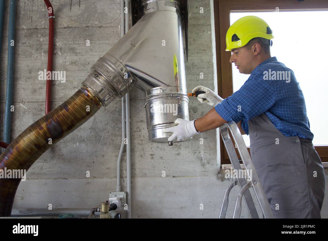 Image of a hard-hatted handyman plumber on a ladder repairing and ...