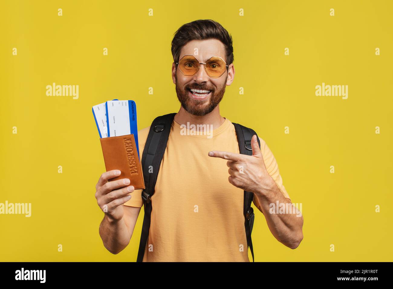 Positive middle aged man with backpack pointing at passport and ...