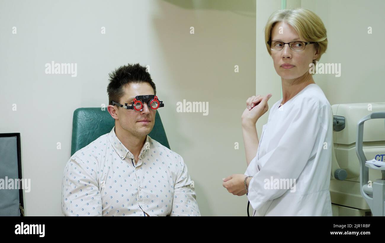 female doctor ophthalmologist is checking the eye vision of handsome ...