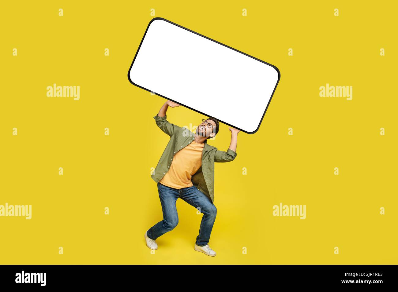 Man holding huge heavy smartphone with blank screen over yellow ...