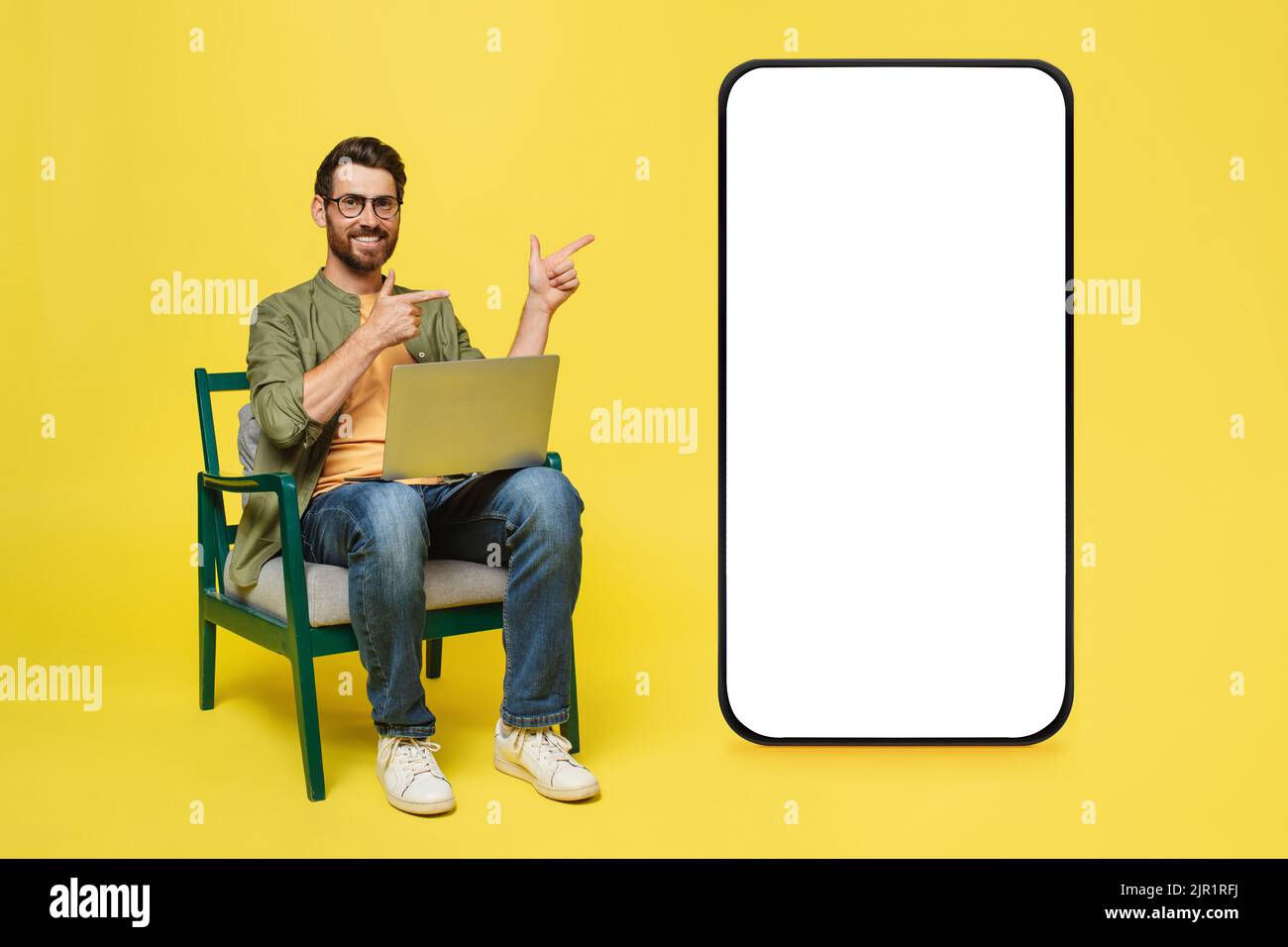 Excited middle aged man sitting on chair using laptop pc and pointing ...