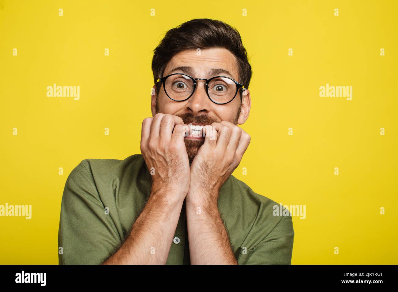 Afraid man biting nails with worry, frightened male looking at camera ...