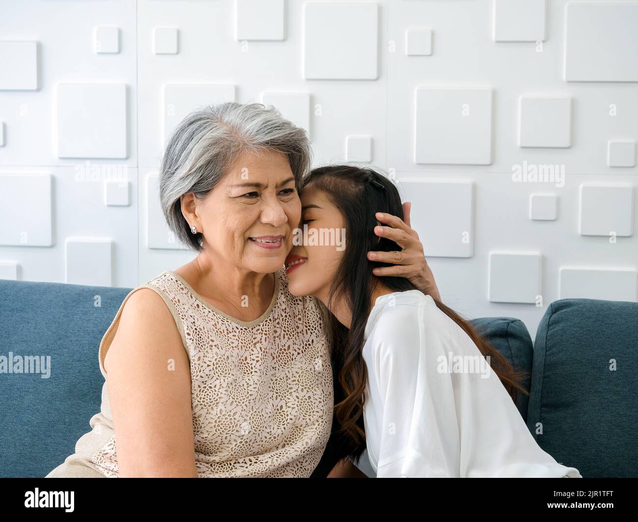 Happy Asian senior, mother white hair embracing her beautiful daughter while she kiss her cheek ...