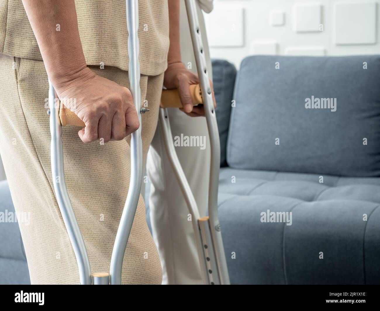 Closeup elderly woman's hands holding on crutches standing in living ...