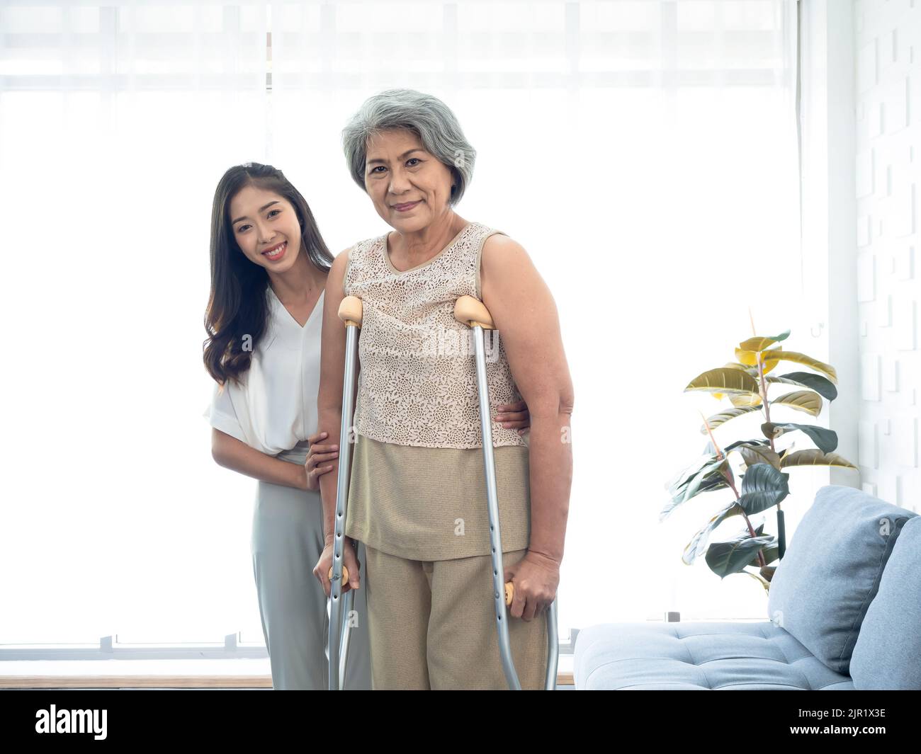 Elderly woman trying to walk on crutches standing held and supported in ...