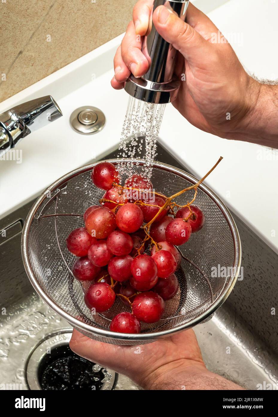 Washing red grapes in a strainer under running water Stock Photo - Alamy