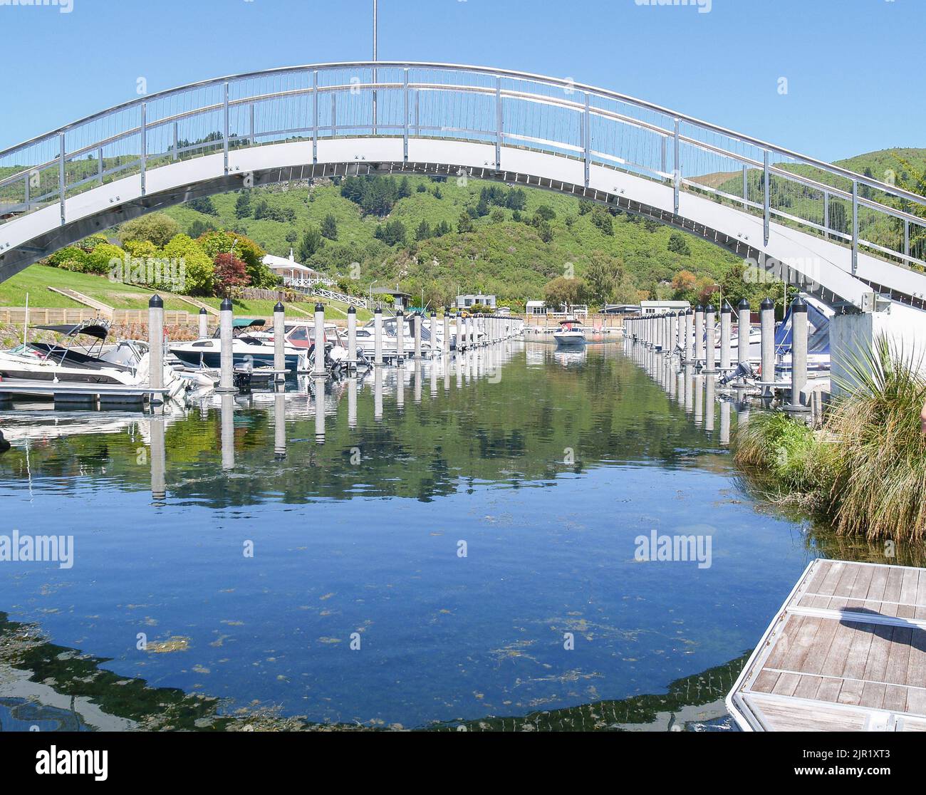 Arching pedestrian bridge structure over marina with moored and ...