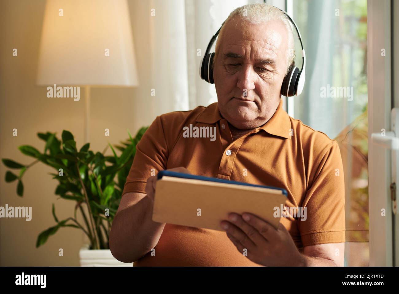 Portrait of frowning senior man wearing headphones when watching ...