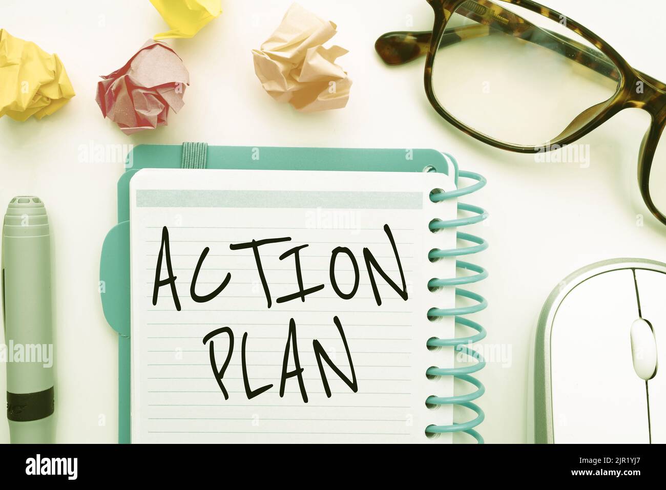 A handwritten ACTION PLAN text on a notebook with some office supplies ...