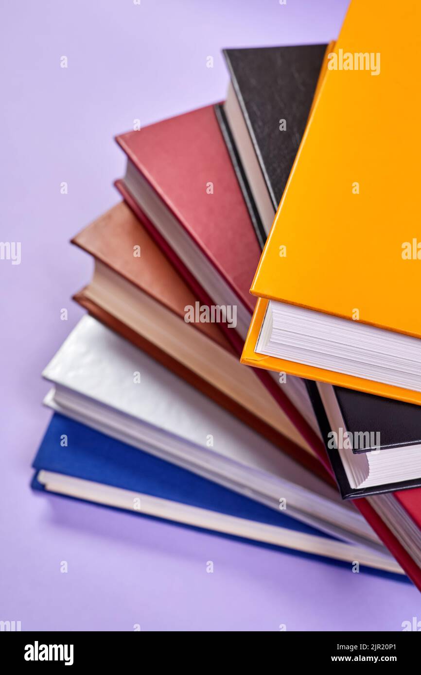 Stack of colorful books on purple background Stock Photo - Alamy