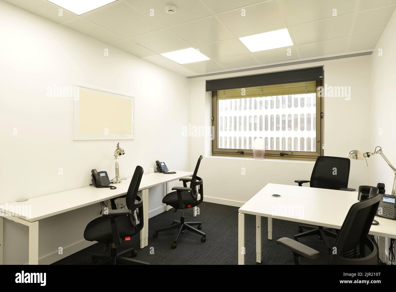 Office cubicle with a small white double table with telephones, black ...