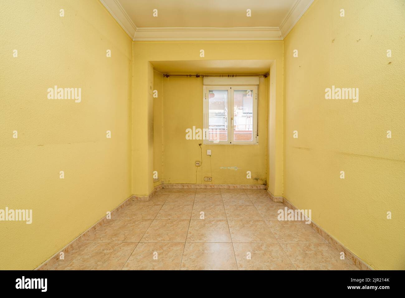 Empty room with light stoneware floor, dirty yellow painted walls ...