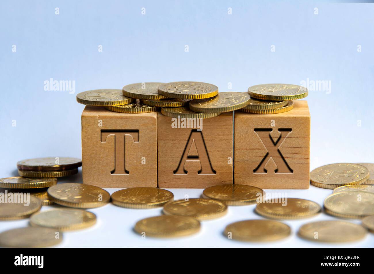 Tax word engraved on wooden block surrounded with gold coins. Taxation ...