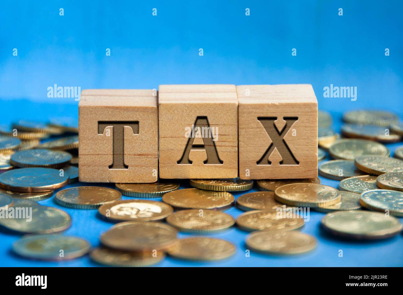 Tax word engraved on wooden block surrounded with gold coins. Taxation ...