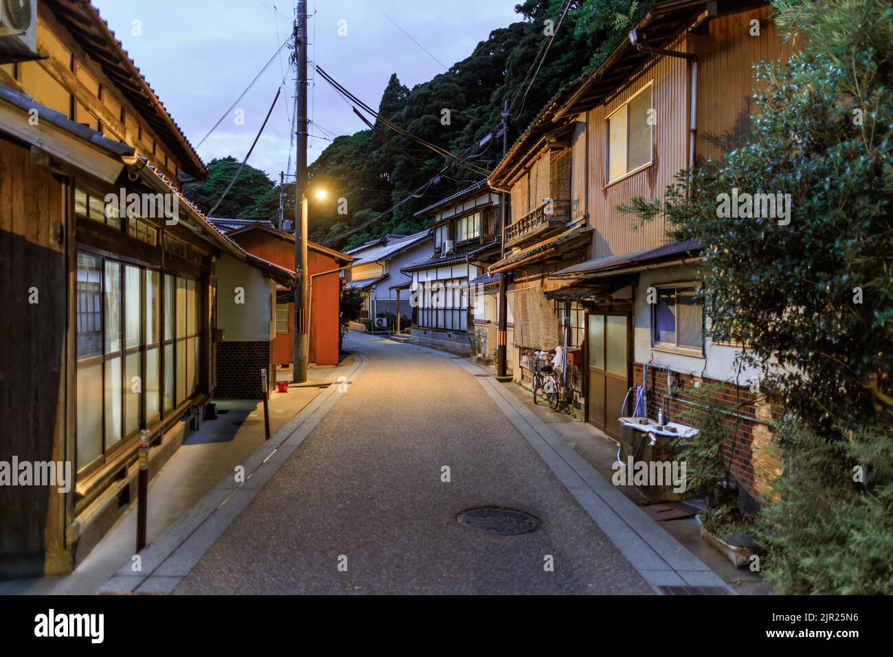 Buildings line deserted road through quiet Japanese village at dusk ...